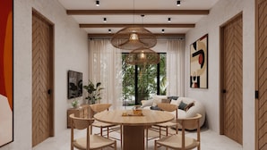 Uma sala de jantar moderna com uma mesa de madeira redonda, seis cadeiras e um lustre central.