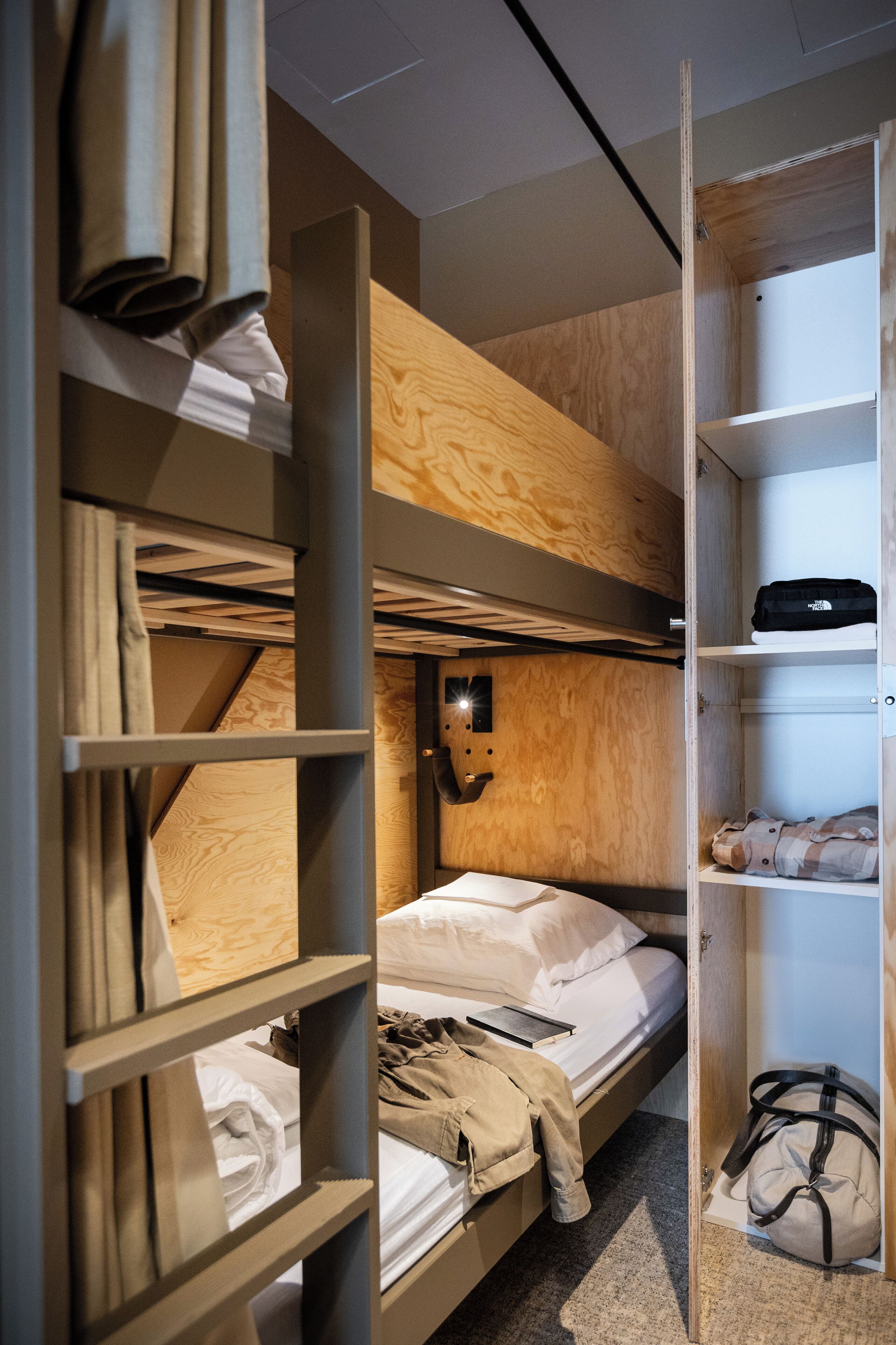 Quarto com beliche de madeira, mesa de cabeceira e guarda-roupa com prateleiras.