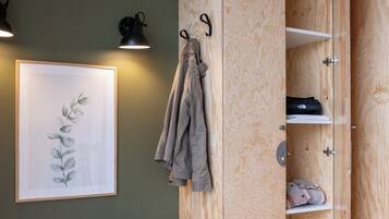Quarto com guarda-roupa de madeira, escrivaninha com um laptop, uma bolsa e um quadro na parede.