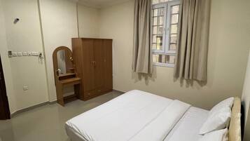 Quarto com cama, guarda-roupa, espelho, janela com cortinas e ventoinha no teto.