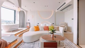Uma sala de estar moderna com um sofá curvo, uma mesa de centro redonda, uma janela grande e uma banheira.