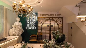 Interior luxuoso com um lustre imponente, uma estátua e uma placa para o 'Curry Castle Restaurant'.