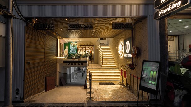 A entrada do The Deep Hotel com placas indicando estacionamento, restaurante e quartos.