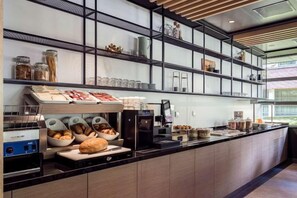 Um balcão de café da manhã com diversas opções de alimentos e uma máquina de café.