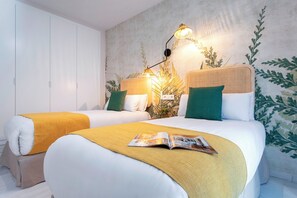 Quarto de hotel com duas camas, um guarda-roupa espaçoso e um mural na parede.