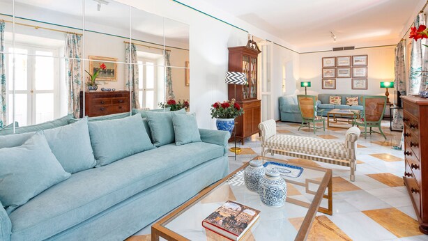 Uma sala de estar com um sofá azul claro, uma mesa de centro e uma área de jantar com cadeiras e uma mesa.