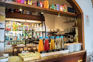 Uma área de bar com prateleiras cheias de garrafas e uma seleção de sumos à frente.