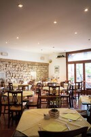 Uma sala de jantar com paredes de pedra, mesas e cadeiras de madeira.