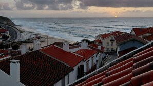Uma cidade costeira com telhados de telhas vermelhas, uma praia e o oceano.