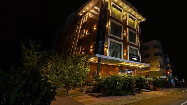 Um hotel moderno com fachada bem iluminada, grandes janelas e uma placa indicando que se trata de um alojamento 'Townhouse'.