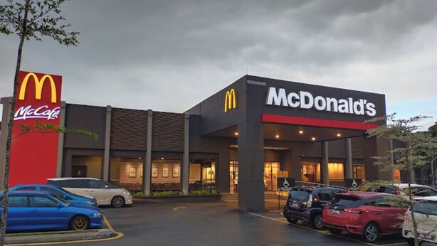 Um restaurante McDonald's com design moderno, com um letreiro grande e várias vagas de estacionamento.