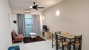 Uma sala de estar moderna com um sofá, uma mesinha, uma mesa de jantar com cadeiras, um ventilador de teto e uma TV.