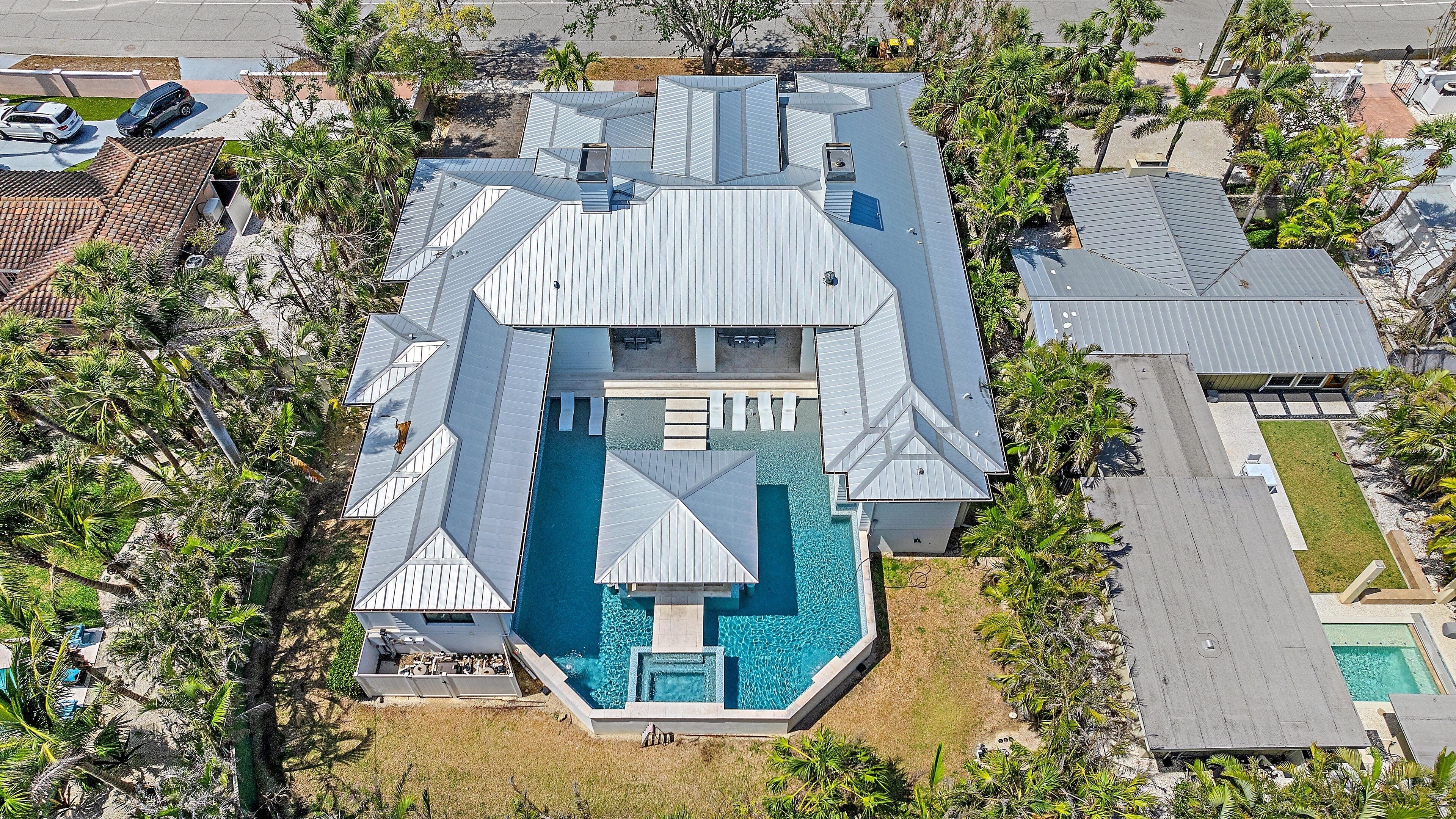 Uma casa grande com piscina, cercada por palmeiras e um gramado bem cuidado.