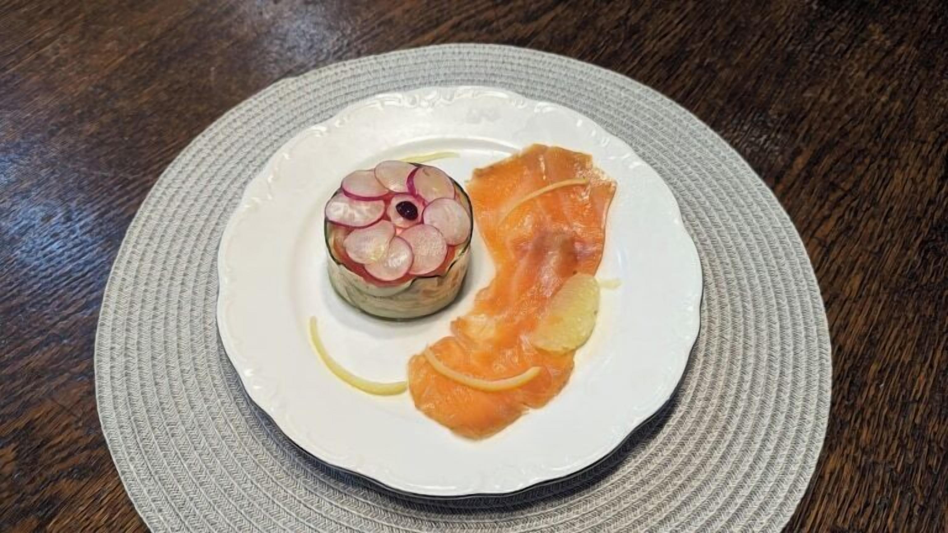 Um prato com salmão e um pequeno recipiente redondo com fatias de rabanete.