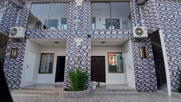 Um edifício de dois andares com fachada em azulejos, janelas amplas e uma entrada central.