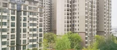 Um edifício residencial alto, com vários andares, cercado por áreas verdes e um pequeno parque.