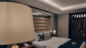 Quarto de hotel moderno com uma cama grande, mesas de cabeceira, uma luminária e vista para o exterior através de uma janela com persianas.