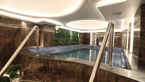 Piscina interior moderna com interior em mármore, envolvida por uma barreira de vidro e grades de metal.