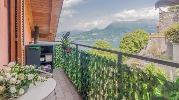 Varanda com vista para montanhas e um lago, teto de madeira e plantas em vasos.