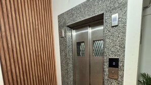 Um elevador com acabamento metálico, um painel de controle e uma parede texturizada.