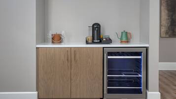 Uma cozinha com geladeira embutida, cafeteira e chaleira sobre a bancada.