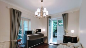 Um quarto com uma cama, uma escrivaninha com computador, uma cadeira, um aparador e um candelabro.