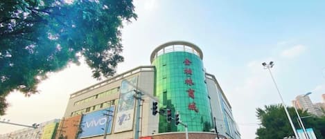 Um edifício de vários andares com uma seção cilíndrica destacada e sinalização indicando uma área comercial.