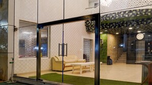 Um interior moderno com divisória de vidro, um sofá, uma mesa de centro e uma escada que dá acesso a um elevador.
