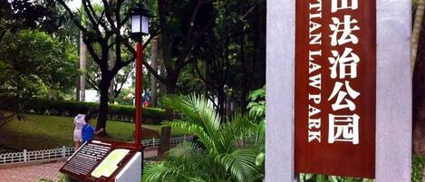 Placa indicativa do Parque Jing Tian Law, com uma placa comemorativa e um lampião ao fundo.