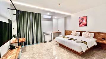 Quarto de hotel moderno com uma cama grande, uma escrivaninha, um espelho e uma cortina verde.