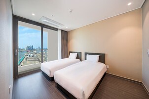 Quarto de hotel com duas camas, uma janela grande com vista para a cidade e design moderno.
