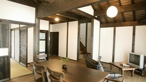 Um interior tradicional com uma mesa de jantar de madeira, cadeiras, uma televisão e uma escada.