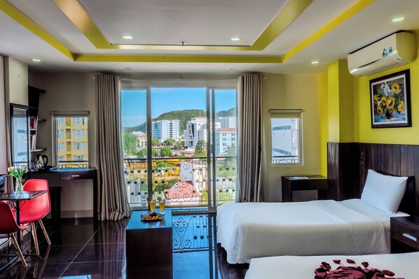 Quarto de hotel com varanda, mesa de escritório, cama e área de refeições.