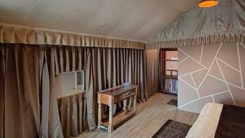 Um quarto espaçoso com teto alto, ventoinha no teto, mesa consola de madeira, cama com colcha branca e parede com padrão geométrico.