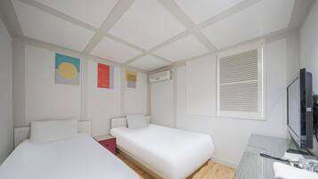 Quarto de hotel com duas camas, uma escrivaninha e uma televisão.