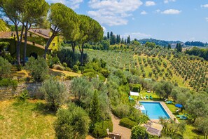 Uma villa com piscina rodeada por oliveiras e árvores.