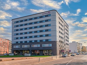 Um hotel moderno com fachada plana, várias janelas e entrada visível com porta de vidro.