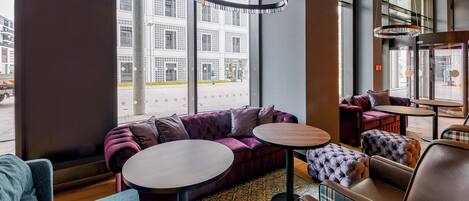 Um interior moderno com um sofá roxo, mesas redondas e um tapete estampado.