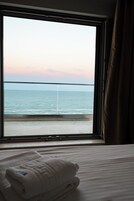 Quarto de hotel com uma grande janela com vista para o mar.