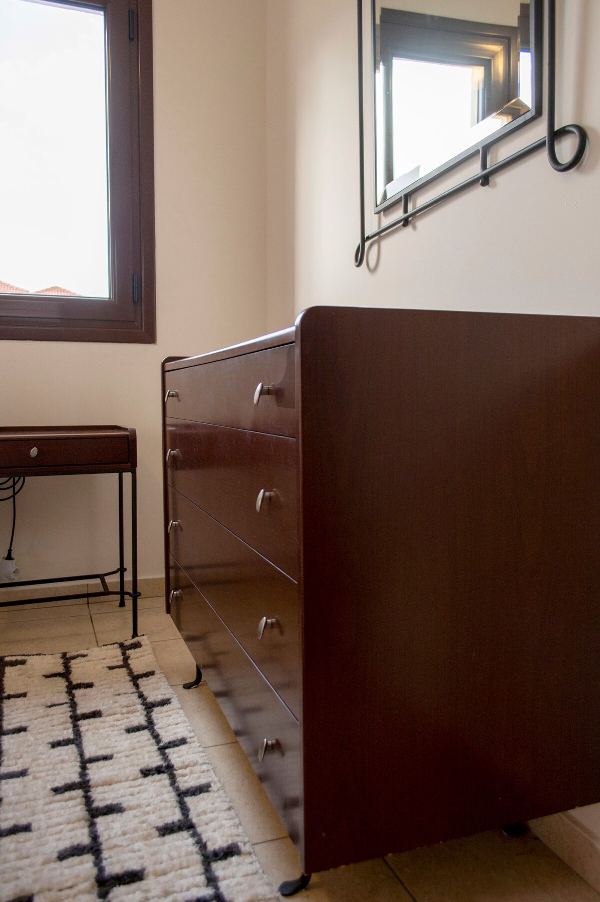 Quarto com penteadeira, espelho e janela.