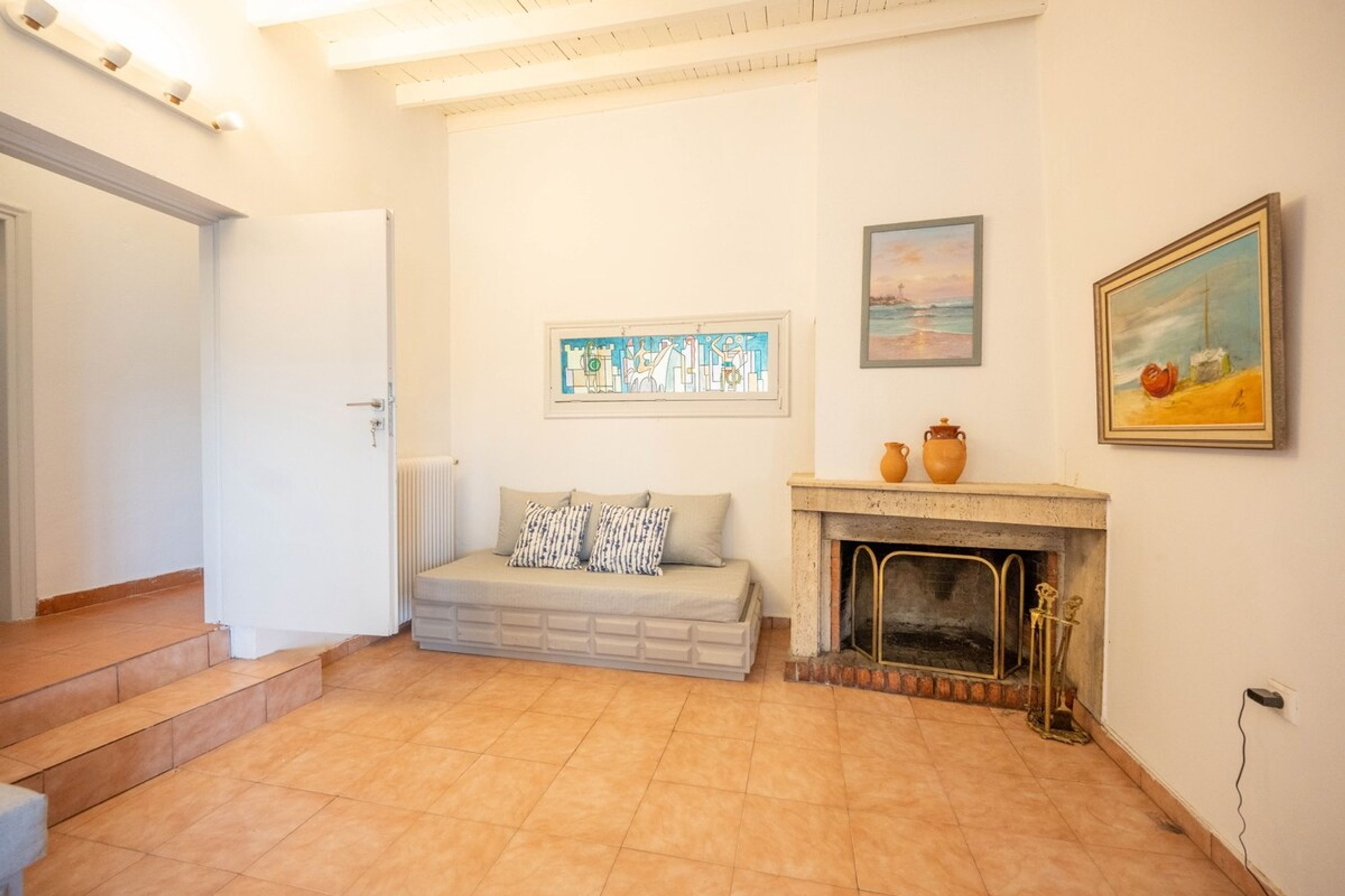 Uma sala de estar com sofá, lareira e obras de arte nas paredes.
