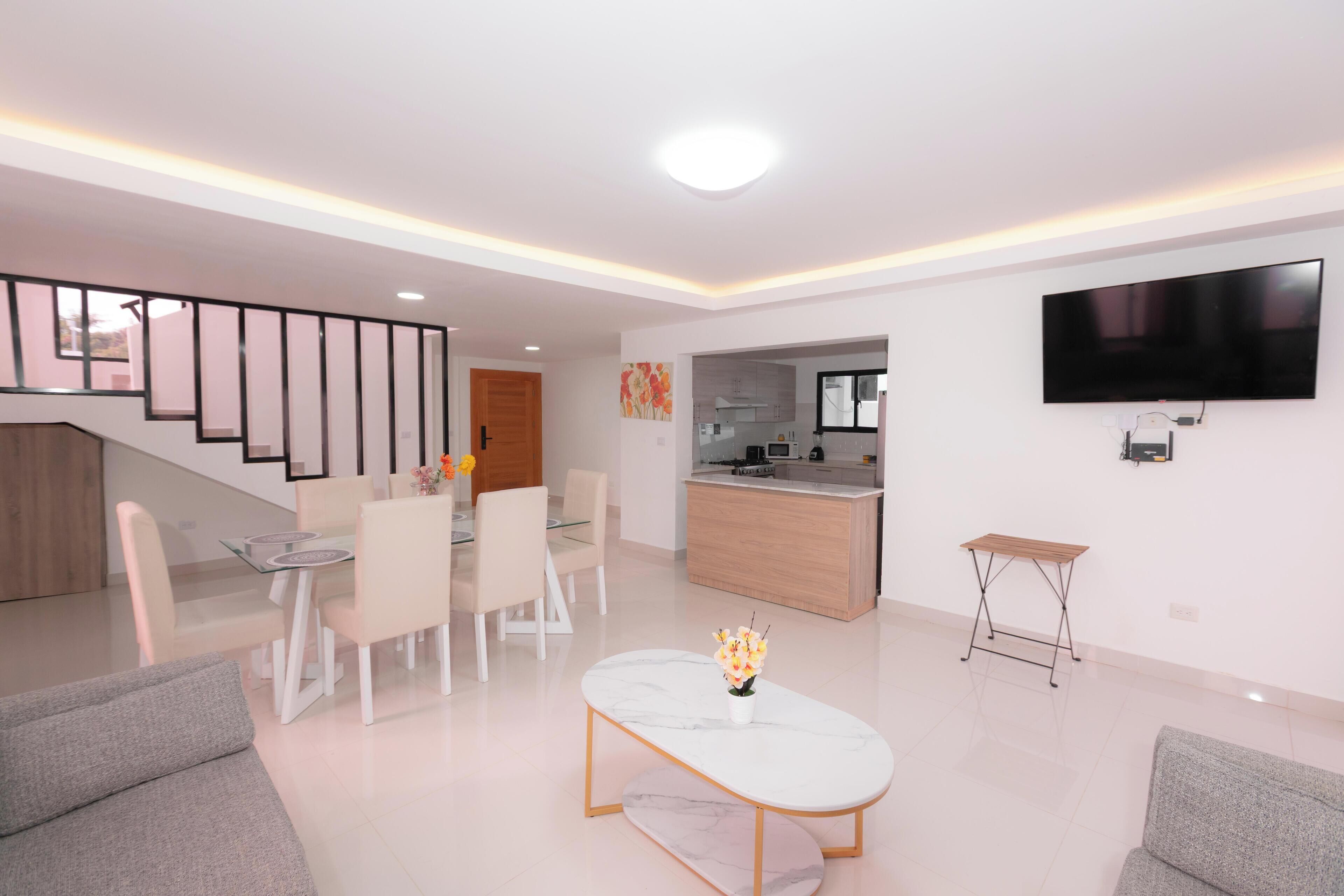 Uma sala moderna com área de jantar, cozinha e escada.