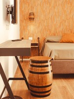 Quarto com um banquinho de madeira, uma cama com almofada laranja e uma mesa com controle remoto.