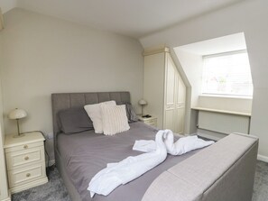 Quarto com cama, mesas de cabeceira, guarda-roupa e uma janela.