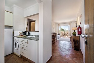 Uma cozinha moderna com armários brancos, máquina de lavar e uma área de jantar com mesa e cadeiras.
