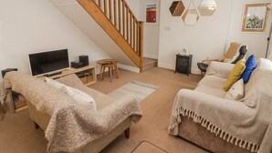 Uma sala de estar aconchegante com escada de madeira, televisão, sofá e mesa de centro.