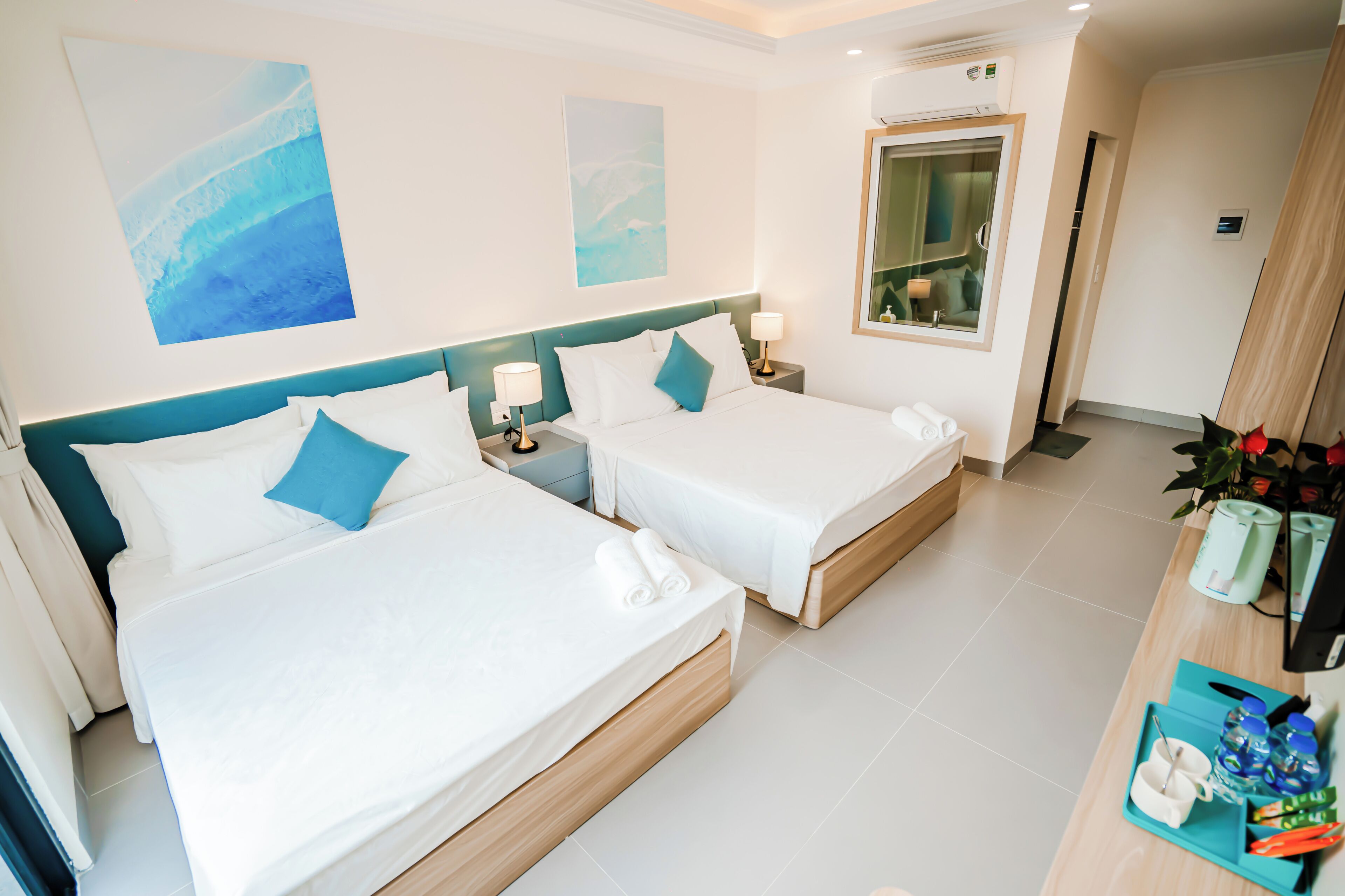 Quarto de hotel com duas camas, um espelho de banheiro e uma pequena mesa com produtos de higiene pessoal.