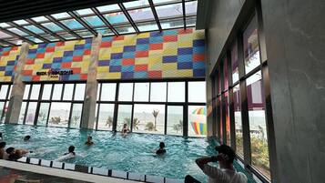 Piscina interna com amplas janelas e parede colorida.