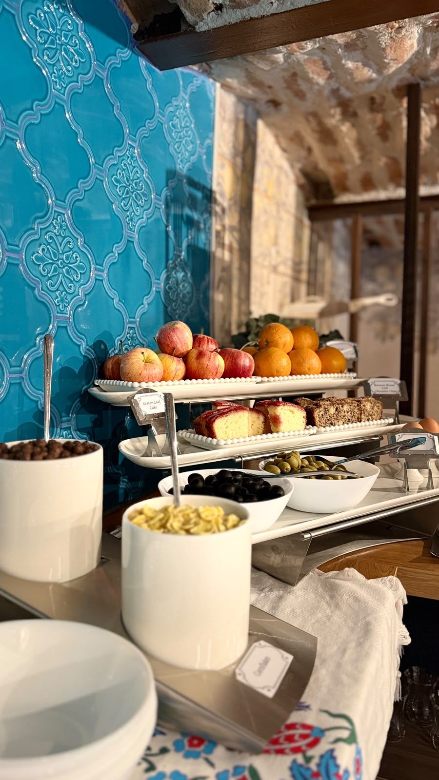 Buffet com diversos alimentos, incluindo frutas, bolos e uma tigela de cereal.