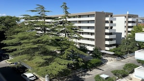 Um edifício com várias andares e varandas, rodeado por árvores.